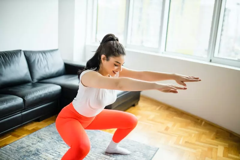 žena robí drep, pohyb, ktorý je typický pre HIIT cvičenie pre začiatočníkov