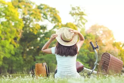 vrouw zit in de buurt van haar fiets in park