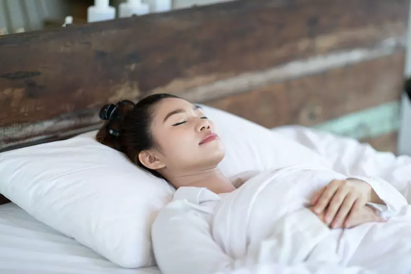 Mulher dormindo na cama, ouvindo ruído branco.