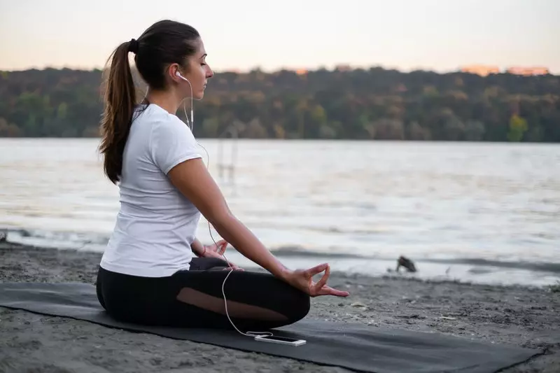 Vacker ung kvinna övar meditation på flodstranden