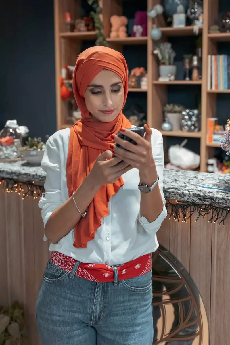 Una donna che indossa l'hijab usa un'app di produttività sul suo telefono. Habit Tracker e Notion sono due altamente...