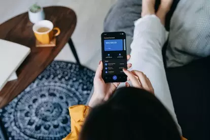 Vista dall'alto di una giovane donna che si rilassa sul divano di una casa accogliente, utilizzando l'app di produttività.