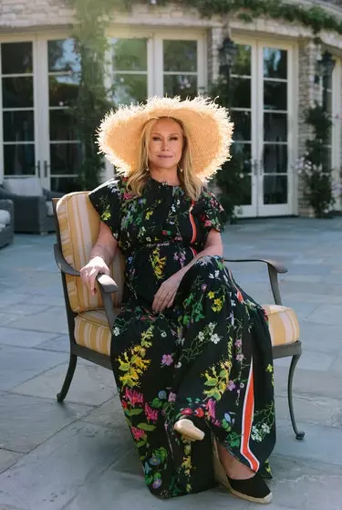 Kathy Hilton li ser kursiyek li derve li ser hewşekê rûdine û cil û bergek reş li xwe kiriye.