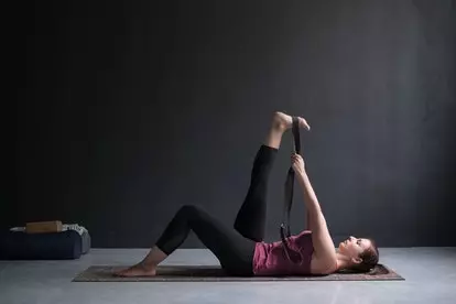 Cara melakukan pose recline big toe untuk meregangkan paha belakang.