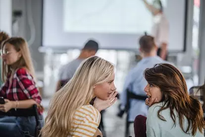 Froulike kolleezje studinten roddel wylst se op in seminar op 'e kampus.