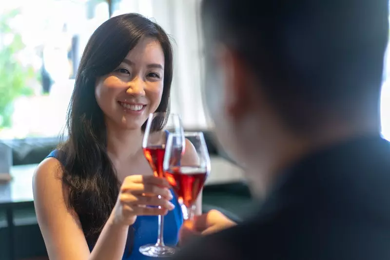 Mooie jonge Aziatische vrouw met een toast met haar partner in een restaurant.